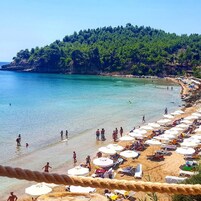 Na praia, espreguiçadeiras, guarda-sóis, toalhas de praia 