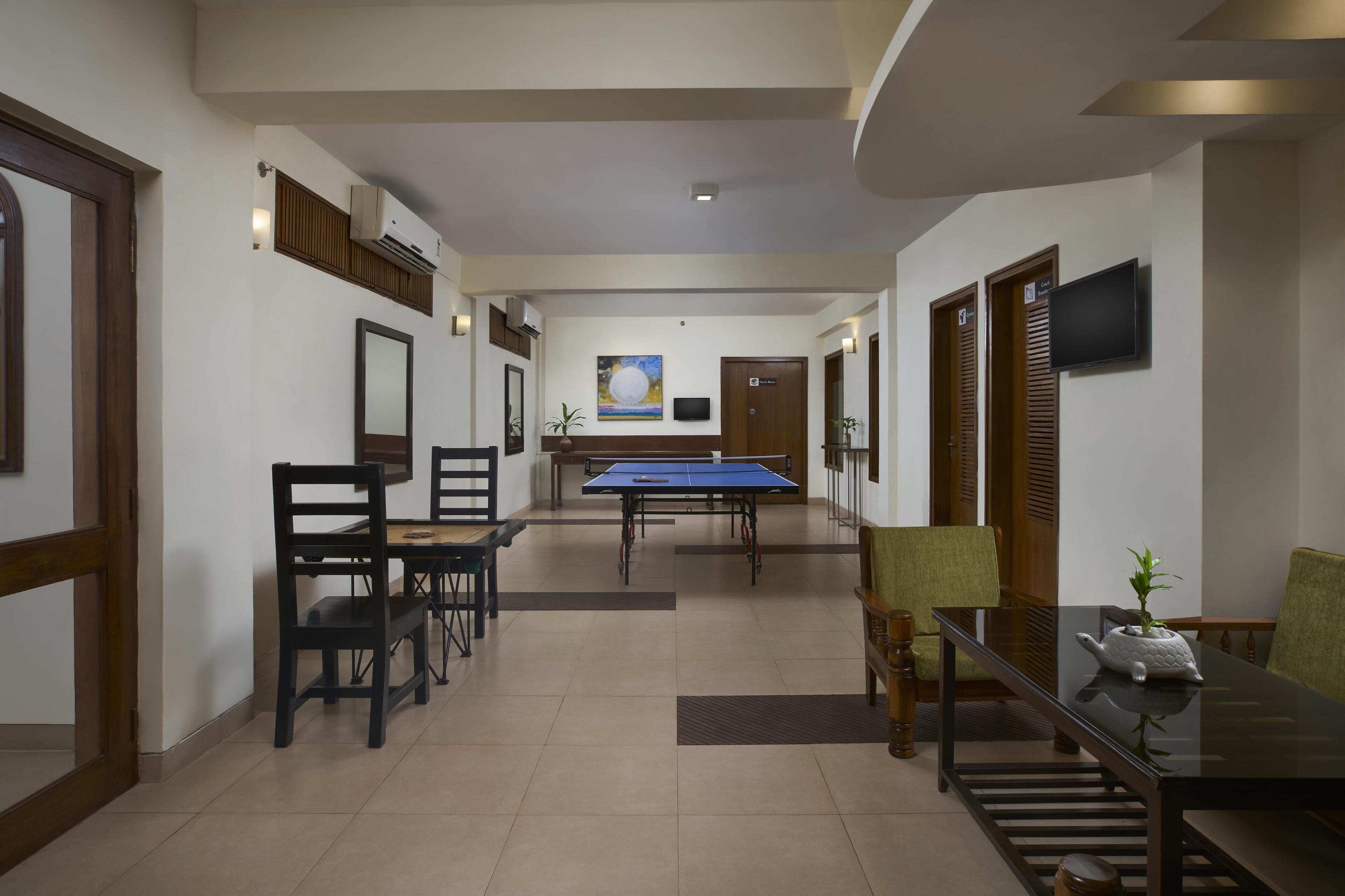 Um saguão de hotel com mesa de pingue-pongue, área de estar e uma televisão.