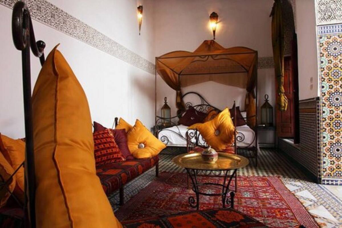 Quarto marroquino tradicional com uma cama, um sofá, uma mesa e paredes com padrões.