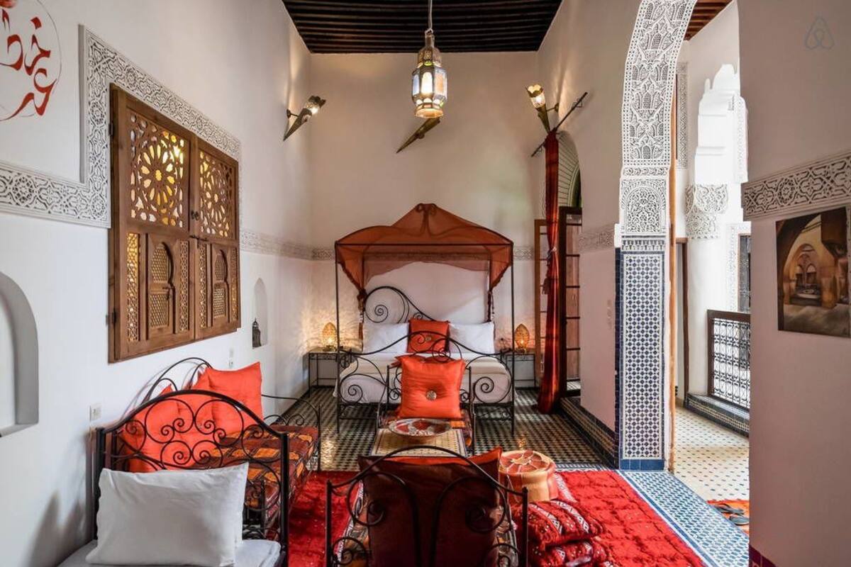 Quarto marroquino tradicional com uma cama, um sofá e um painel decorativo.