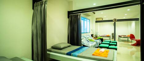 Quarto de hotel moderno com uma cama, uma secretária pequena e uma área de estar com almofadas.