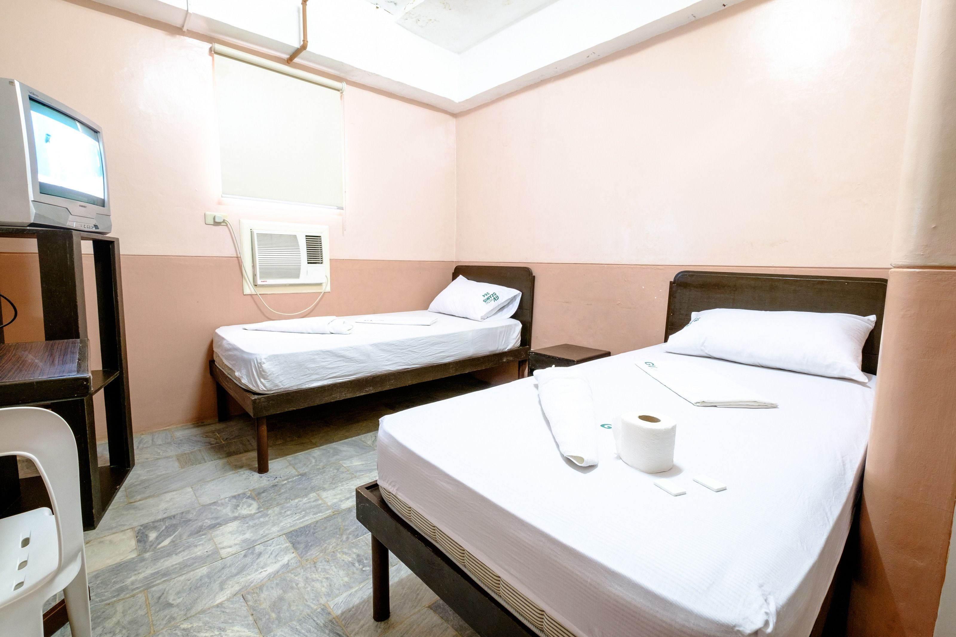 Quarto de hotel com duas camas, televisão, escrivaninha e uma cadeira.