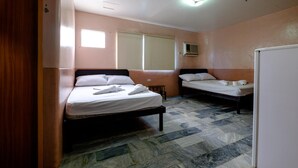 Quarto de hotel com duas camas, geladeira, janela e ventilador de teto.