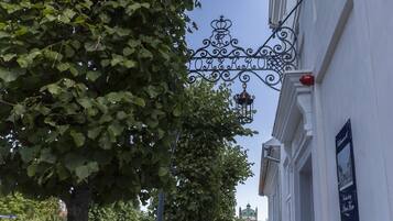 Uma rua com um edifício branco, uma placa de ferro forjado e um poste de luz.