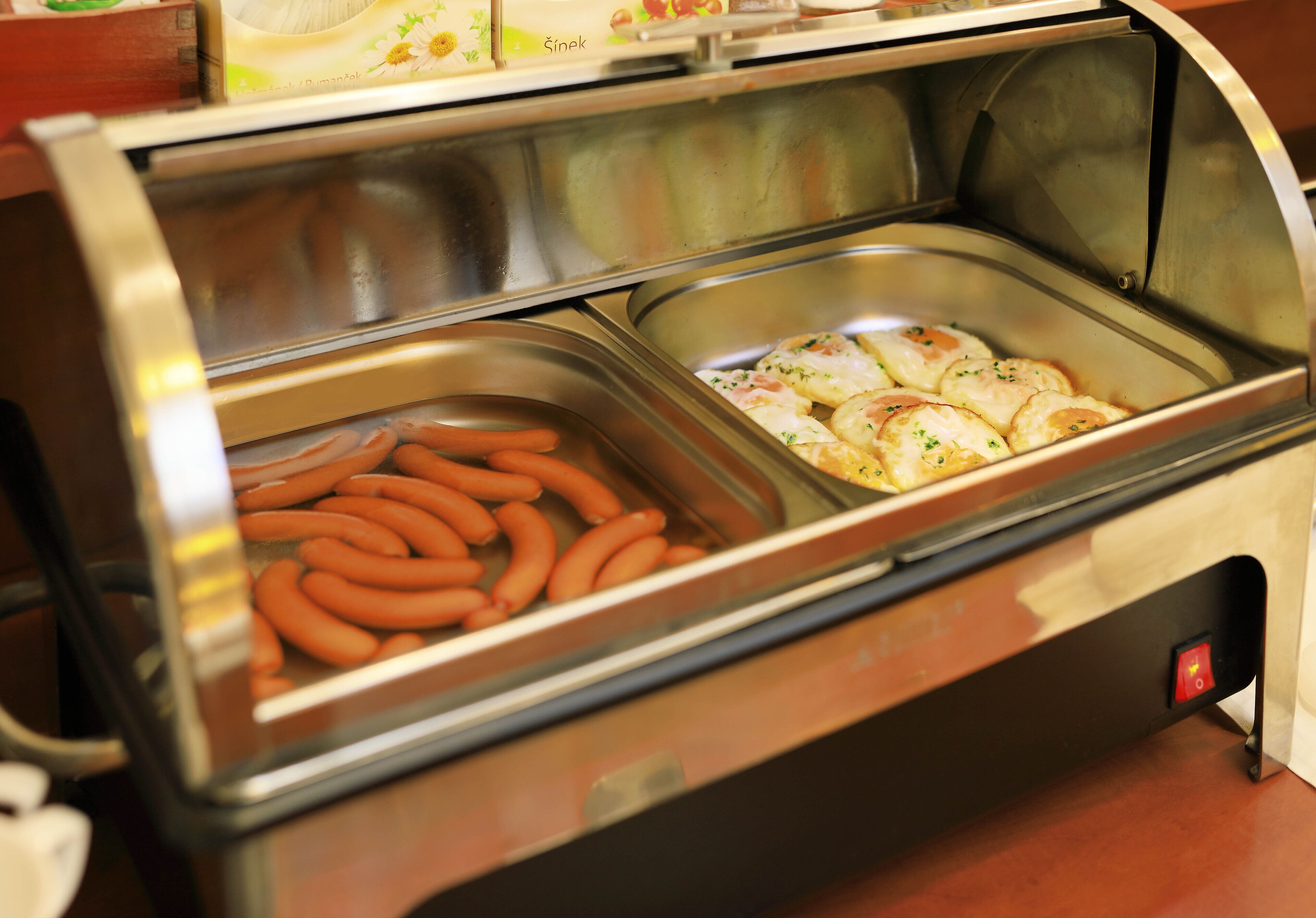 Buffet com diversos alimentos, incluindo salsichas e ovos.