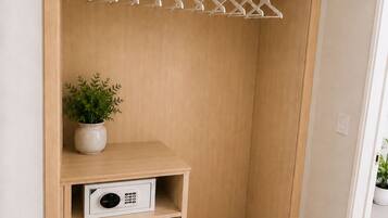 Um closet espaçoso com porta de madeira, barra para pendurar roupas, planta em vaso e eletrodoméstico embutido.