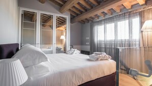 Quarto com cama, guarda-roupa, varanda com corrimão e janela com cortinas.