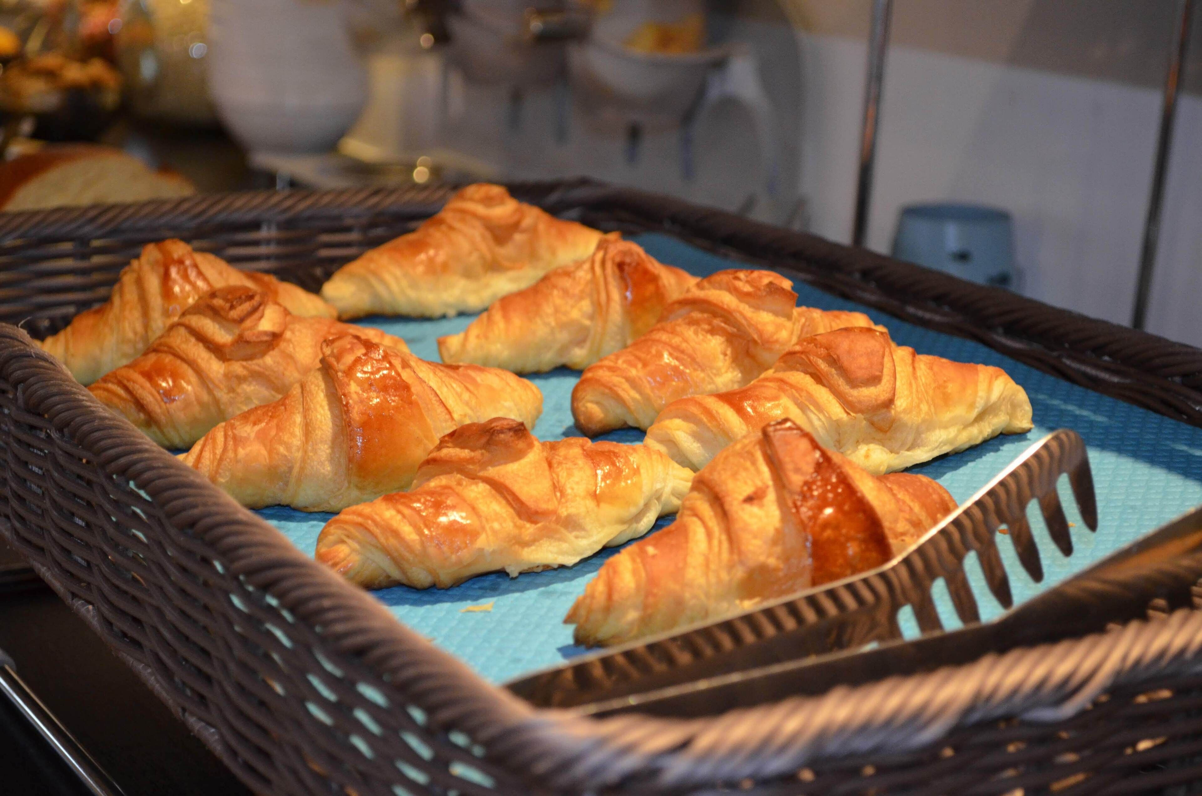 Uma bandeja com croissants sobre uma assadeira azul.