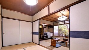 Um quarto japonês tradicional com chão de tatame, portas deslizantes e teto de madeira baixo.