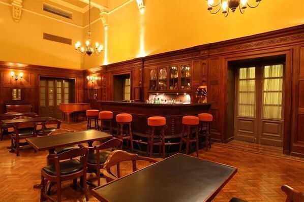 Uma área de bar com mobiliário de madeira, um piano e um balcão.