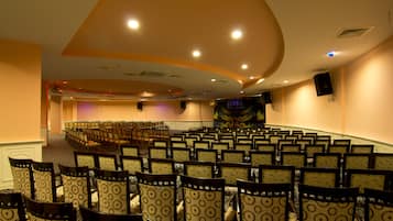 Uma sala de conferências com fileiras de cadeiras, um palco e um banner com a inscrição 'LYRA'.