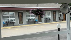 Um motel com uma fileira de janelas, bancos e um cesto de flores pendurado.