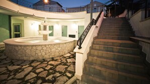 Um pátio com uma fonte de pedra, uma escadaria e um edifício com varandas.