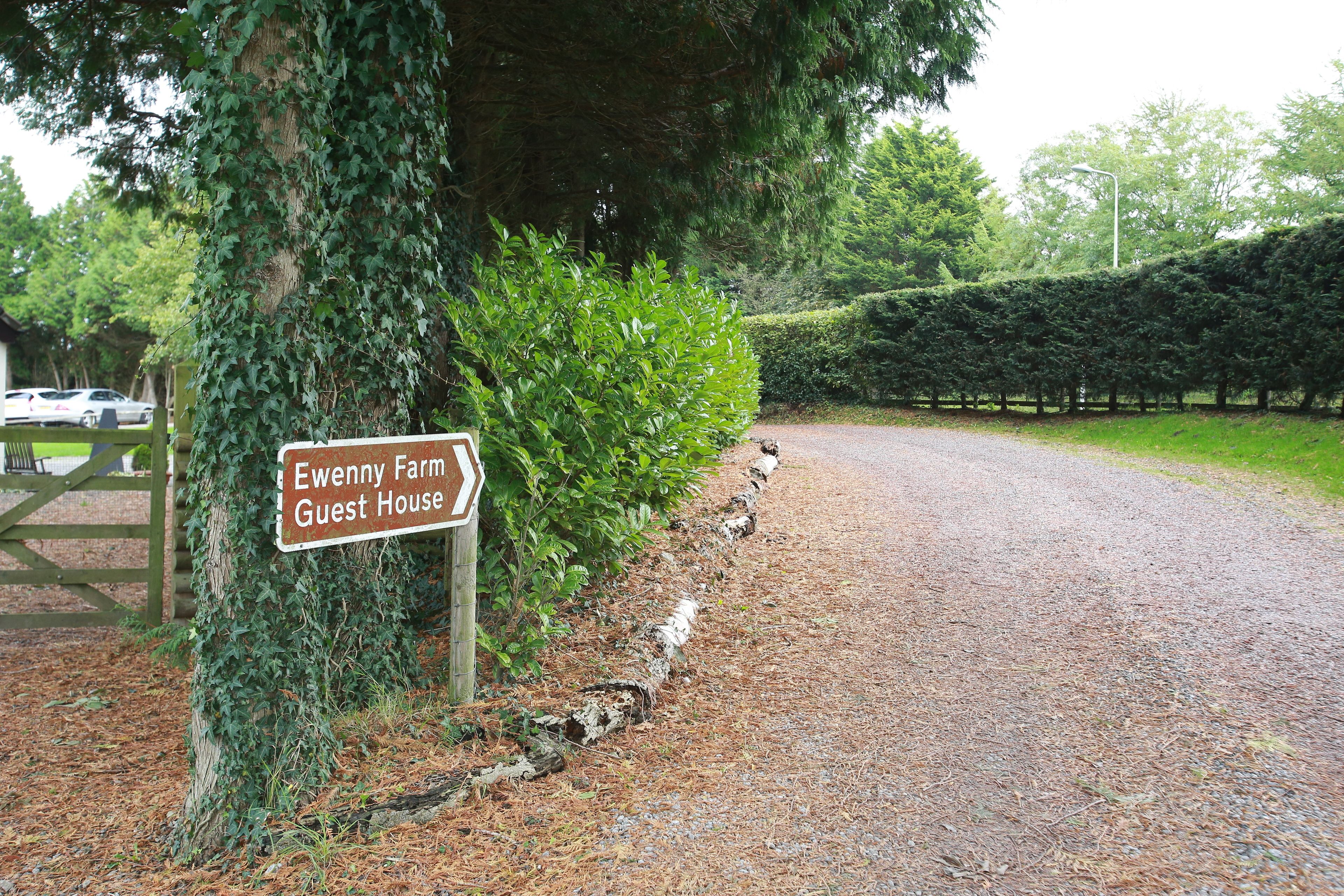 Uma trilha de cascalho conduzindo a uma placa indicando Ewenny Farm Guest House.
