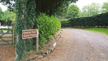 Uma trilha de cascalho conduzindo a uma placa indicando Ewenny Farm Guest House.
