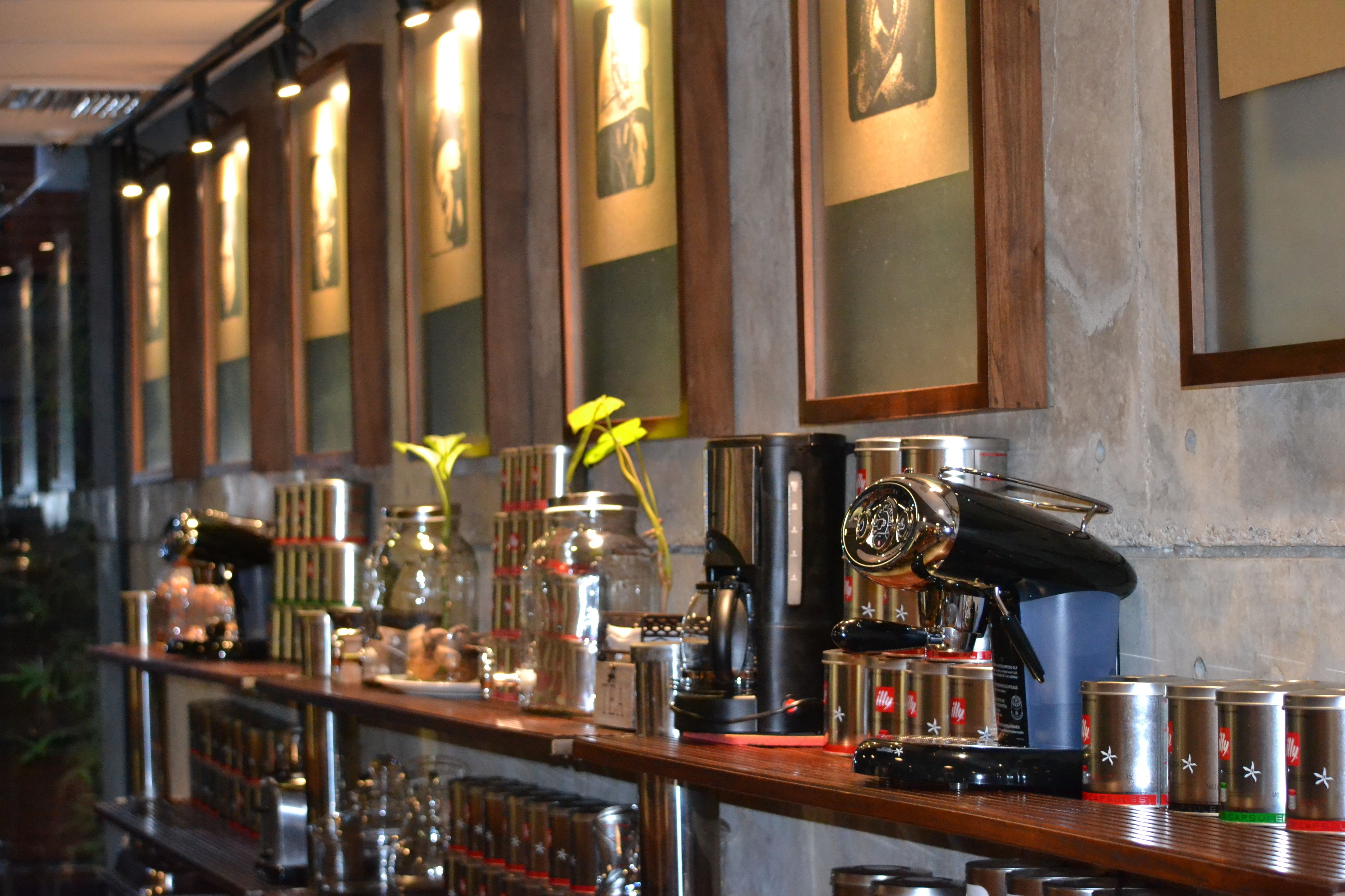 Uma área de bar com prateleiras cheias de copos, potes e uma máquina de café.