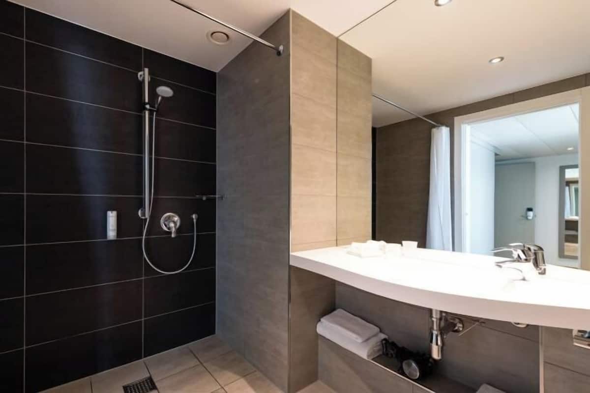 Casa de banho | Um polibã, um chuveiro fixo, artigos de higiene pessoal grátis