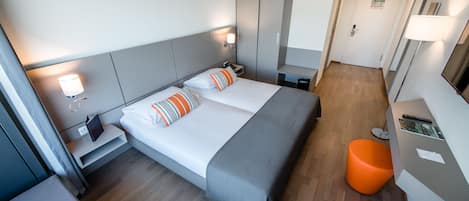 Quarto de hotel com cama, mesas de cabeceira, escrivaninha e espelho.