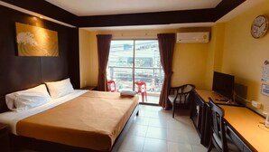 Quarto de hotel com cama, escrivaninha e cadeira, televisão e vista para o exterior.