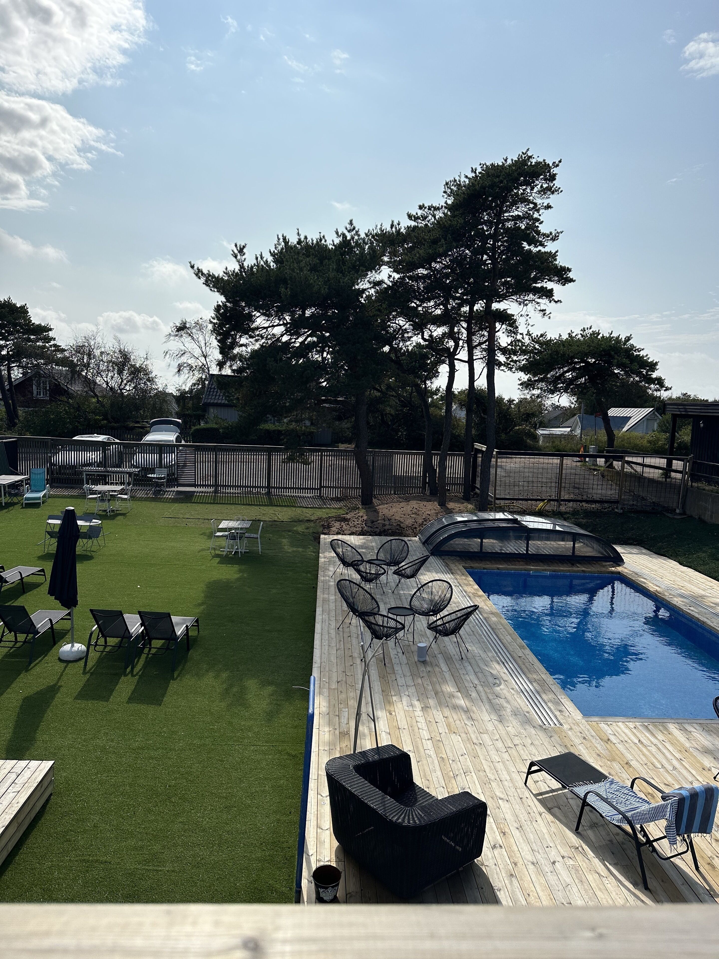 Um quintal com um deck de madeira, uma piscina e móveis de exterior.