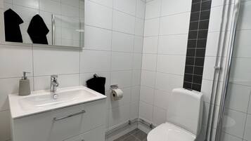 Um banheiro moderno com pia branca, espelho e vaso sanitário.