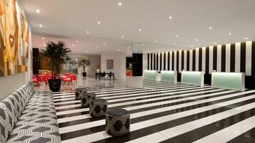 Um hall moderno com piso listrado em preto e branco, um sofá comprido com padrão preto e branco e uma área de recepção com parede listrada em preto e branco.
