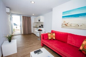 Uma sala de estar moderna com um sofá vermelho, uma mesa de centro branca e um quadro de uma praia.