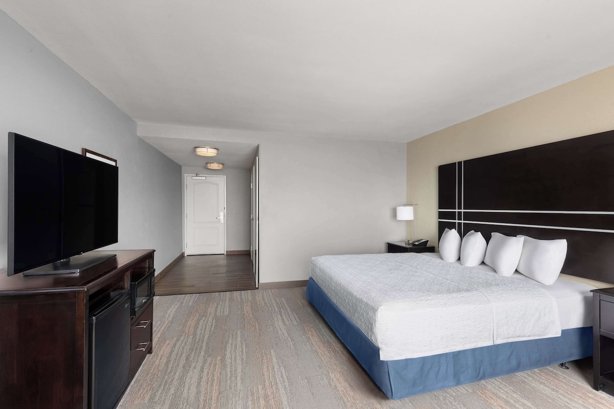Quarto de hotel moderno com uma cama grande, uma televisão de tela plana, uma escrivaninha e uma mesa de cabeceira.