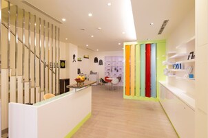 Uma área de recepção moderna com escadas, balcão de atendimento e um espaço de estar com cadeiras.
