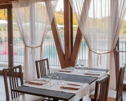 Mesa de jantar posta para dois, com vista para uma piscina e área de estar ao ar livre.