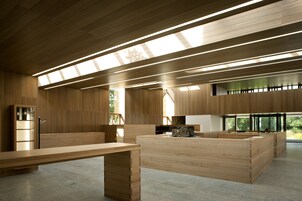 Interior espaçoso e moderno, com painéis de madeira, um longo banco e uma ilha central.