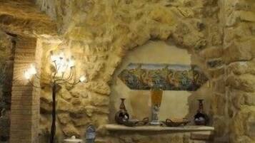 Um quarto com paredes de pedra, um banco embutido e um candelabro.