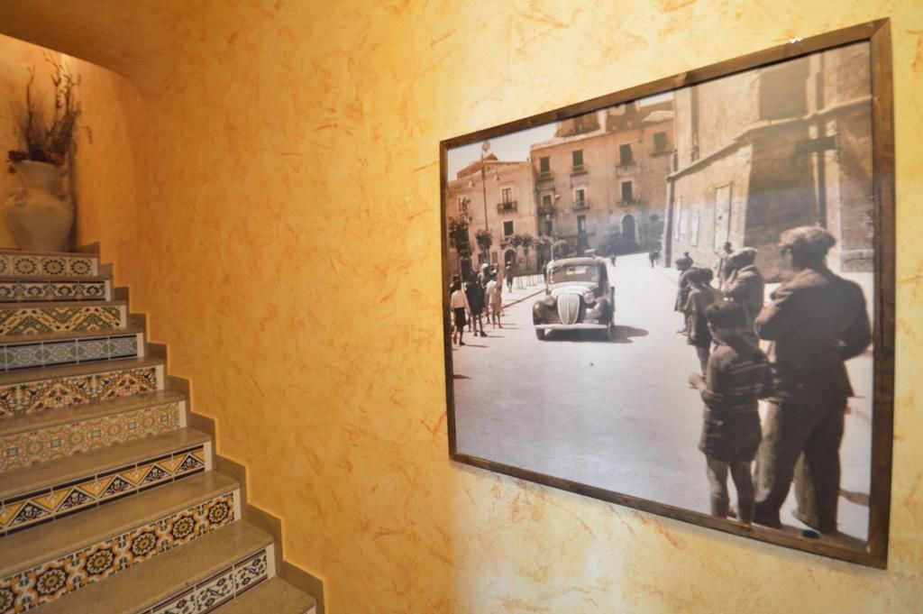Escadaria com azulejos estampados e uma fotografia histórica emoldurada na parede.