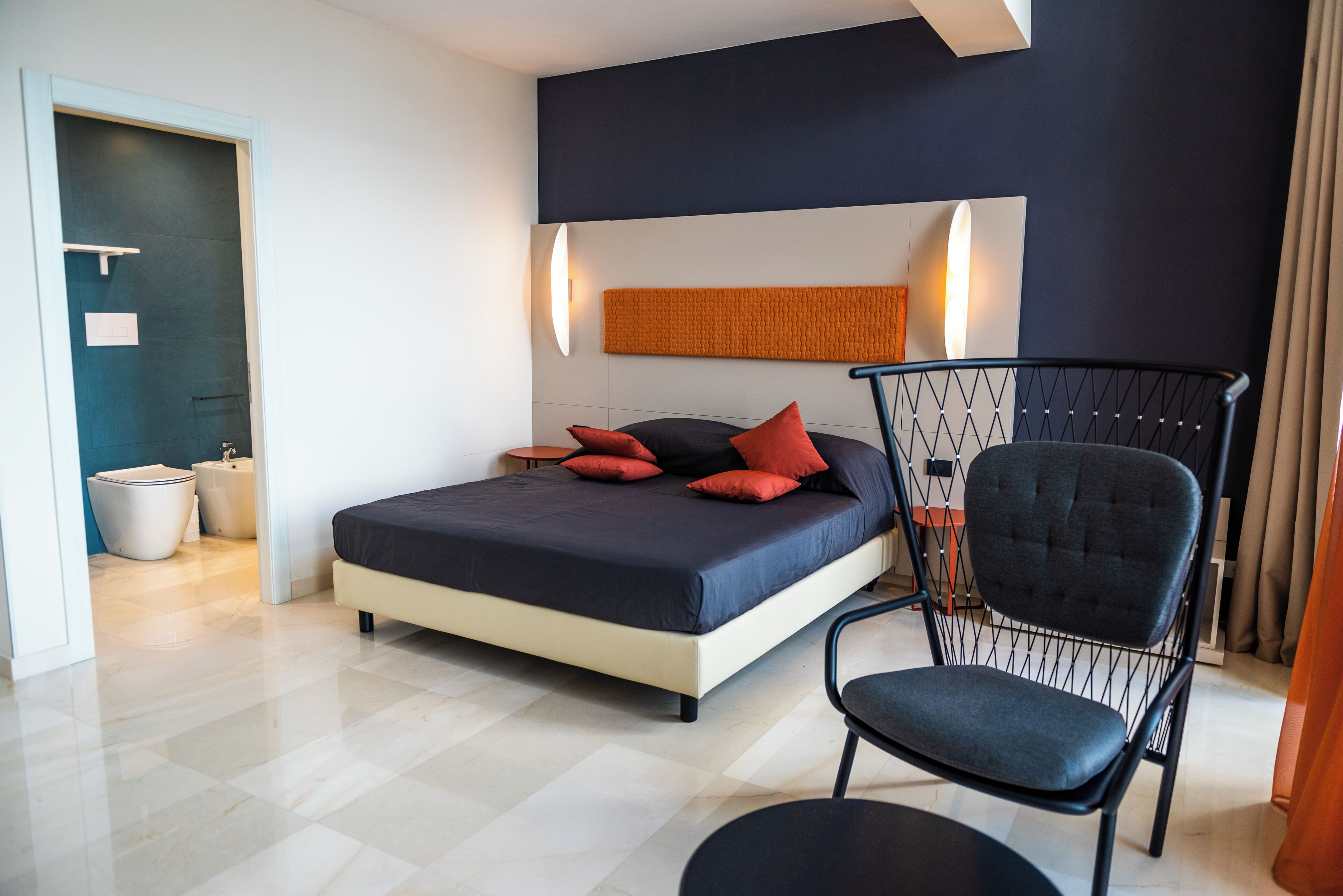 Quarto moderno com uma cama, uma cadeira e uma mesinha de cabeceira.