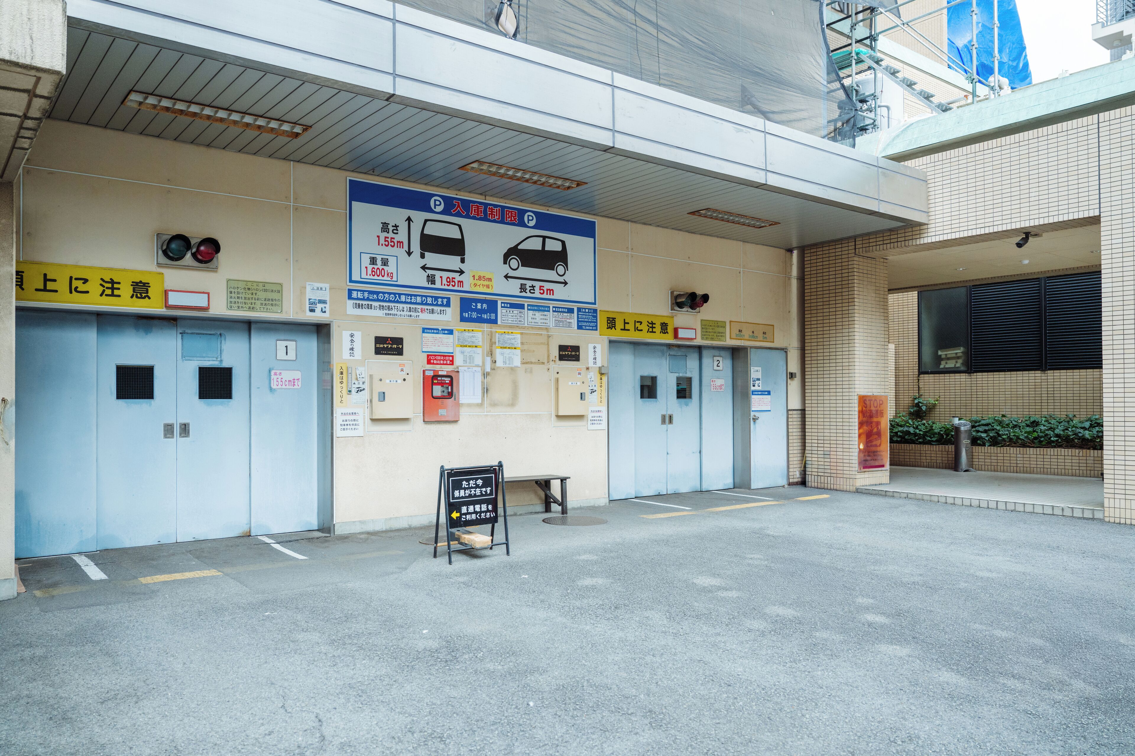 Entrada de um estacionamento com placas de restrição de altura, um banco e placas de sinalização.