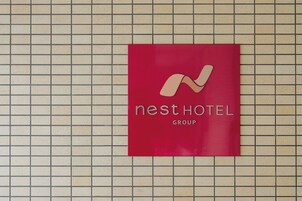 Placa do grupo hoteleiro Nest em uma parede revestida de azulejos.