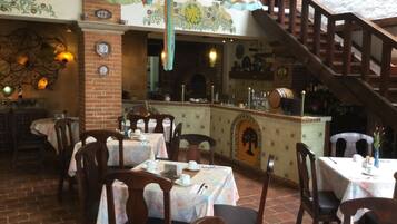 Restaurante com paredes de tijolo, mesas de madeira e luminárias pendentes.