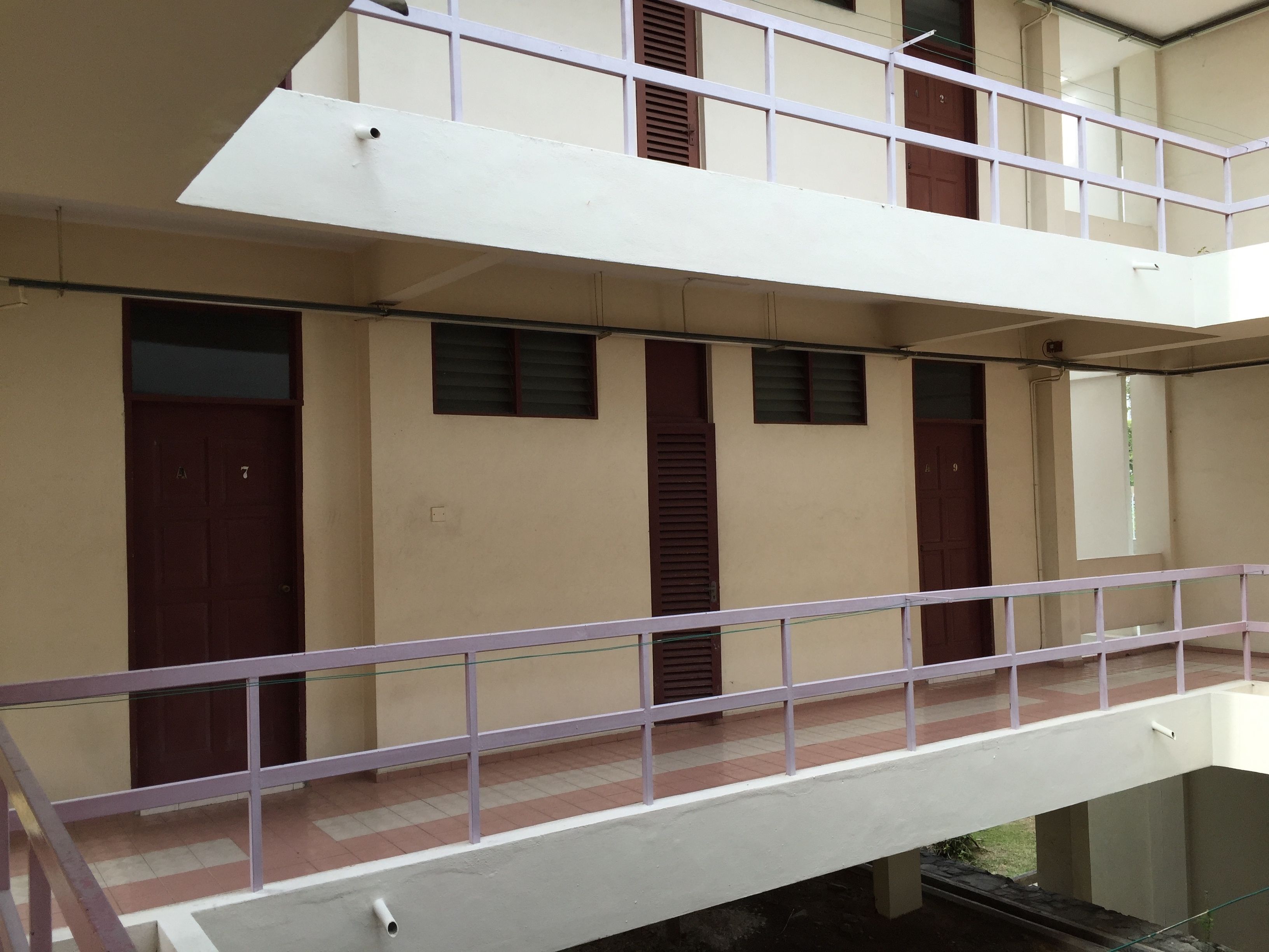 Um edifício com vários níveis, varanda, portas e janelas.
