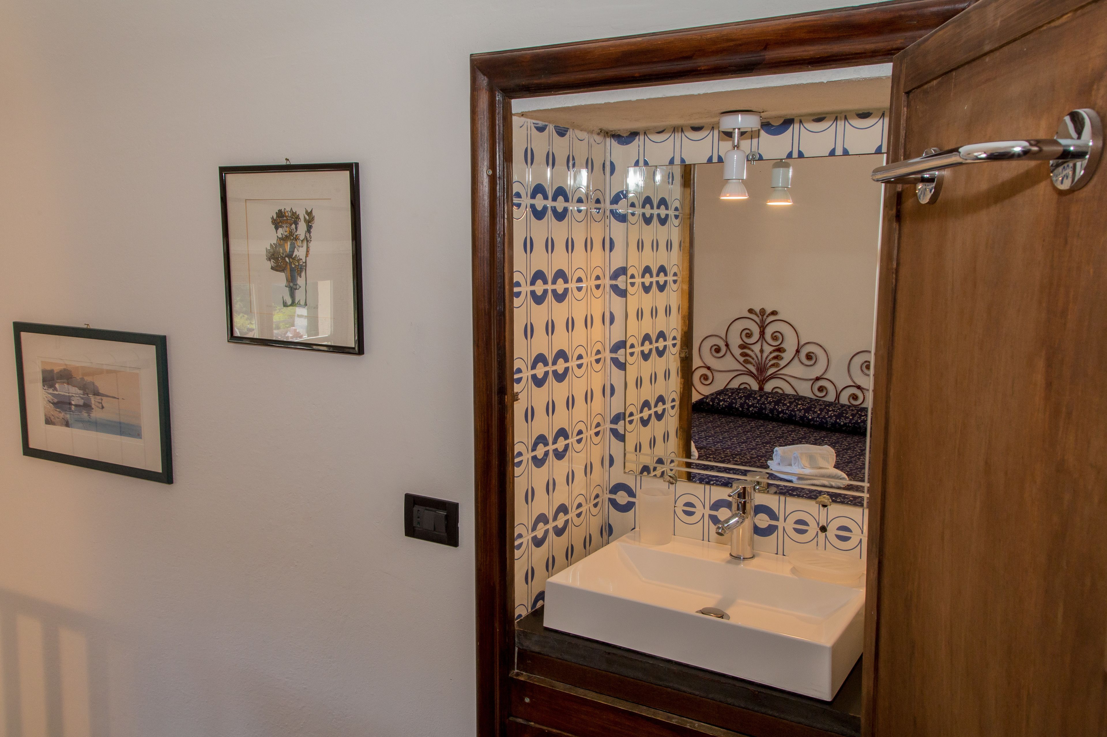 Casa de banho com uma pia branca, um espelho e uma cortina de chuveiro estampada.