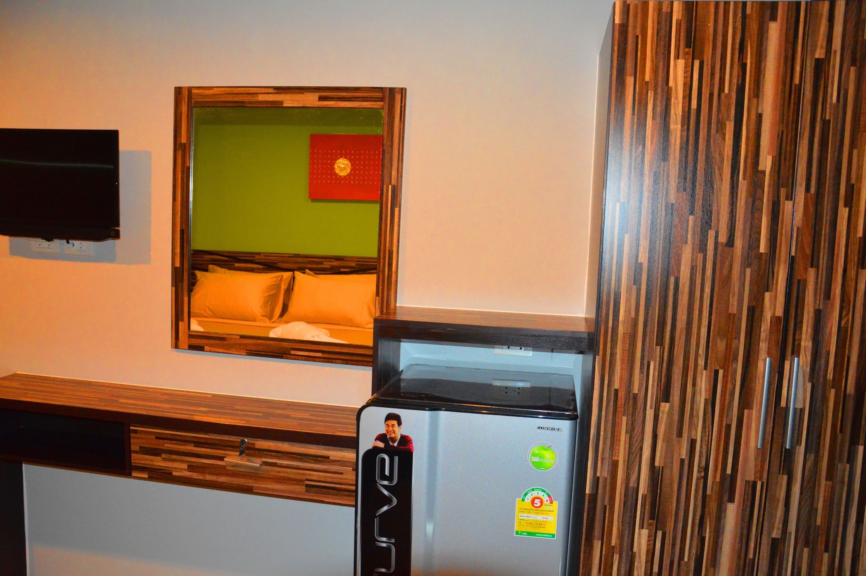 Quarto de hotel com cama, televisão fixada na parede e painel de parede de madeira.