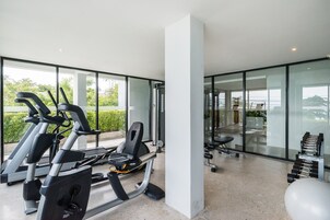 Uma academia moderna com equipamentos de ginástica, janelas amplas e vista para o verde.