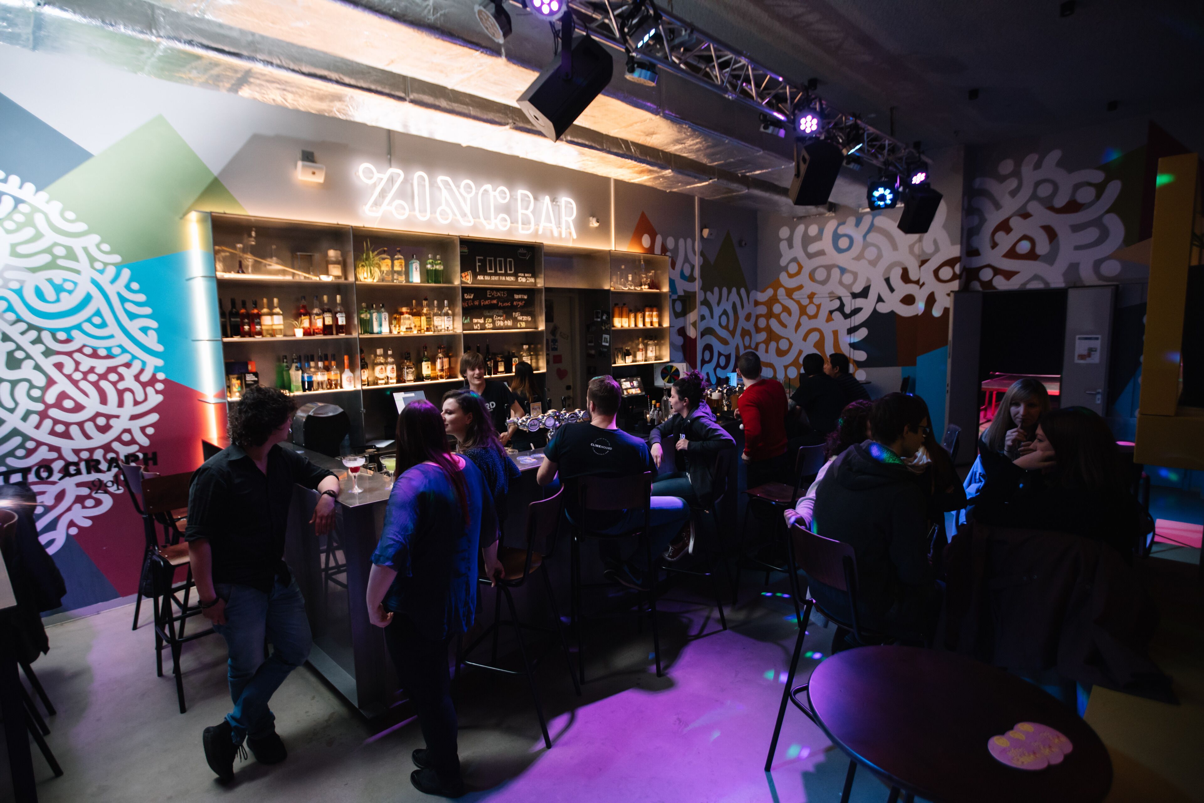 Uma área de bar com prateleiras de garrafas e um letreiro de neon.
