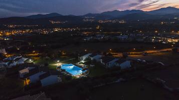 Vista aérea de um bairro residencial com piscina, cercada por casas, com montanhas ao fundo.
