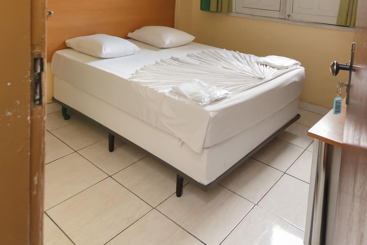Quarto com cama, ventilador de teto, janela com cortinas e parede verde.