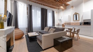 Uma sala de estar moderna com um sofá, mesa de centro e lareira. Há uma área de cozinha com uma mesa de jantar e cadeiras.