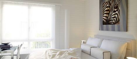 Quarto moderno com uma cama, escrivaninha e janela.