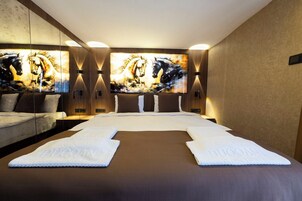 Quarto de hotel com uma cama grande, duas televisões fixadas na parede e um espelho.