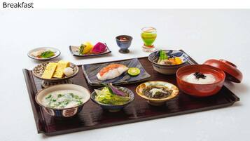 Um café da manhã tradicional japonês disposto em uma bandeja, incluindo diversos pratos como sushi, vegetais em conserva e uma bebida de chá verde.