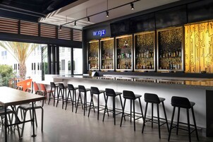 Uma área de bar com balcão, banquetas e um letreiro de neon.