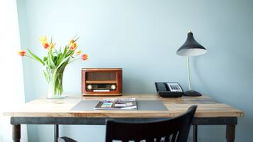 Uma mesa de madeira com um rádio, um telefone e um vaso de flores.